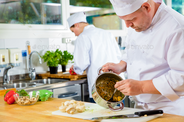 Professional chefs makes food dishes in large kitchen Stock Photo by kjekol