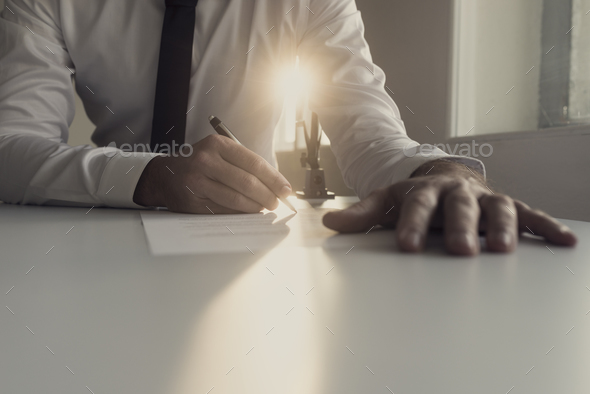 Businessman in white shirt signing document backlit by a shaft o Stock ...