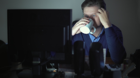 A Man Is Drinking Coffee in the Office at Night at the Computer, Stock ...