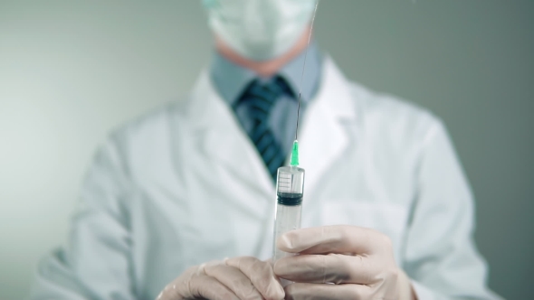 the Doctor Is Preparing for an Injection. Holds a Syringe with Medicine ...