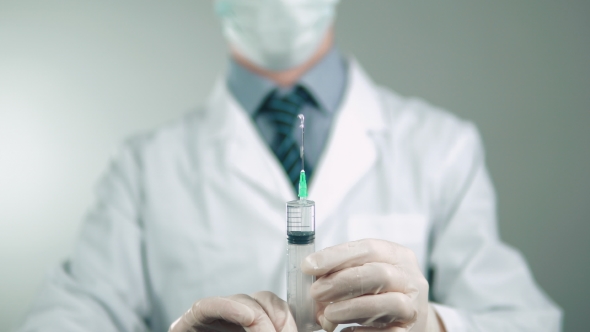 a Doctor in a White Lab Coat and Mask Prepares a Syringe for Injection ...