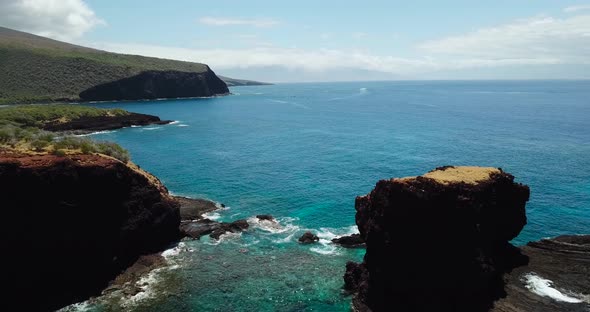 Drone shots of a cliff side beach with blue waters and no one around ...