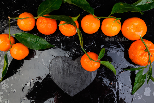 Tangerine around with black slate heart shaped. Stock Photo by bondarillia