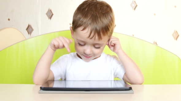 Child Boy Sitting at the Table Touches the Electronic Display of the ...