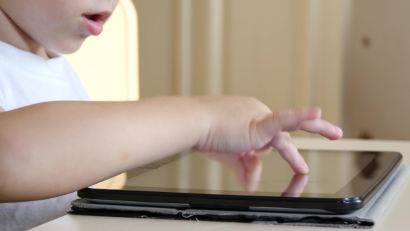 The Little Boy Sitting at the Table Touches the Touch Screen of the ...