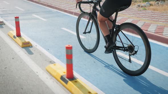 Female road cyclist pushing pedals on bike on bicycle lane at sunny ...