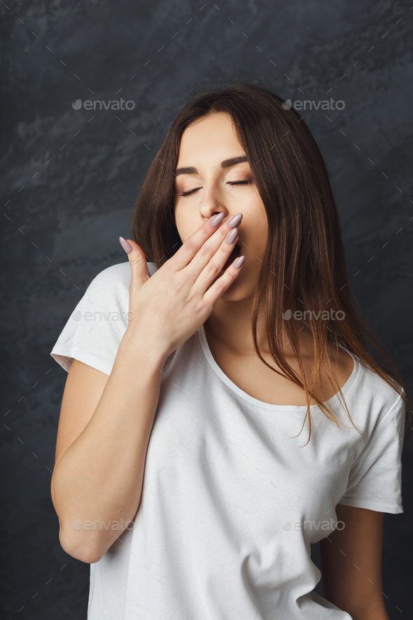 Young woman yawning on dark background Stock Photo by Prostock-studio