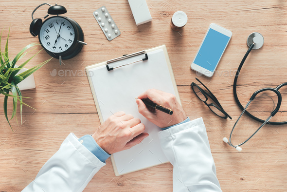 Male doctor writing notes on clipboard paper during medical exam Stock ...