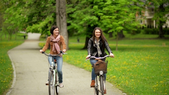 Smiling Brunettes on the Bicycles Are Riding in the Park During the ...