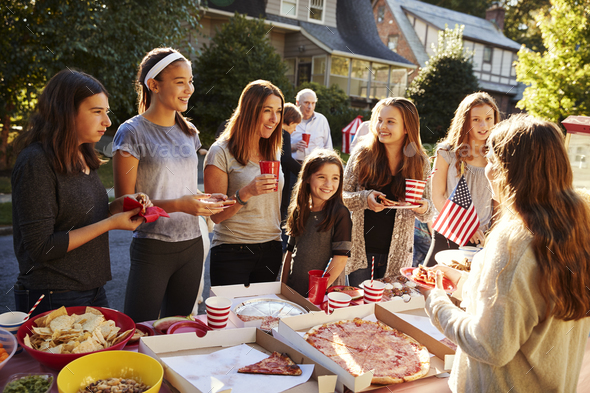 Group of teen girls talking over food table at a block party Stock ...