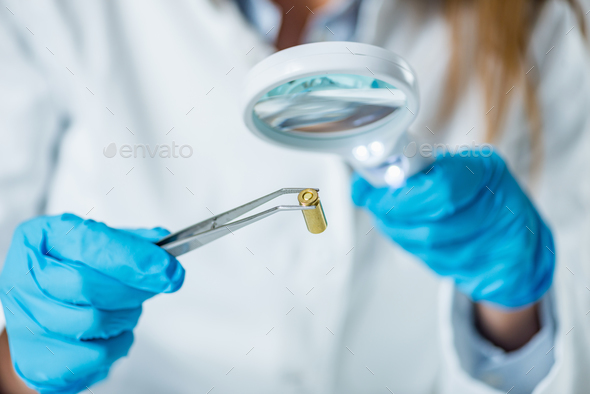 Forensic scientist examining bullet casing Stock Photo by microgen