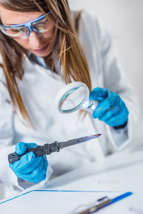 Forensic scientist examining murder weapon Stock Photo by microgen