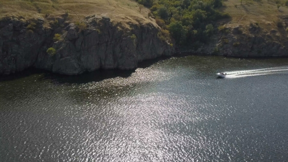 Aerial Follow of Motor Boat Moving Along High Rocks. Sunlight ...