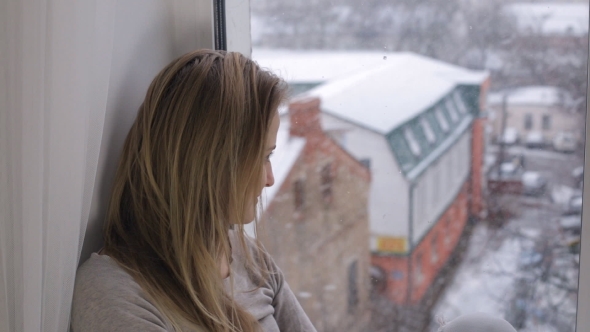 Woman Looking on Snowfall Through Out the Window, Stock Footage | VideoHive