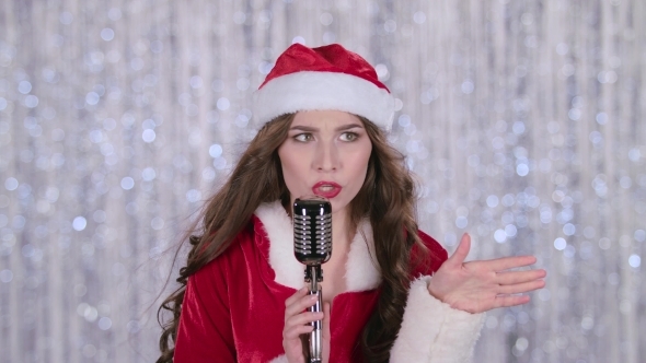 Santa Woman Sings in a Retro Microphone on Bokeh Background, Stock Footage