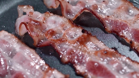 Crispy Pieces of Tasty Bacon Is Fried on the Hot Pan, Hot Boiling Fat ...