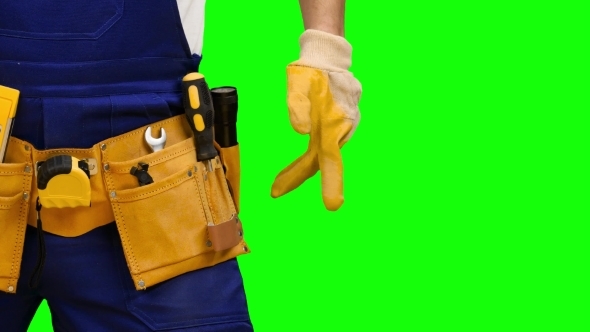 Worker Takes out a Screwdriver from His Construction Belt on Green ...