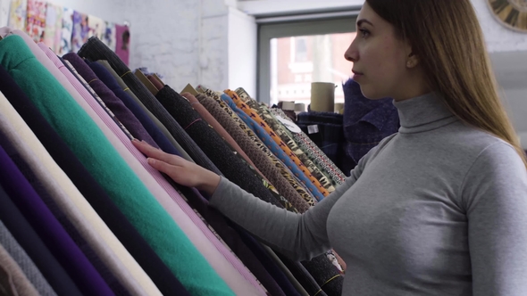 Young Beautiful Woman Chooses the Fabric in a Textile Shop, Stock Footage