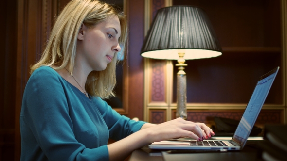 Serious Woman Opening Laptop and Typing on Keyboard on Desk with Table ...