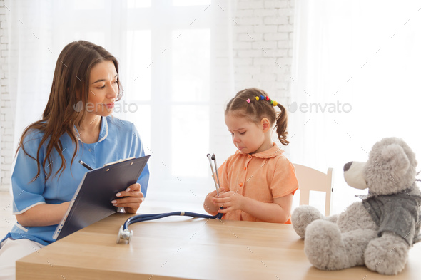 Child girl at the reception of a pediatrician. Stock Photo by Vladdeep
