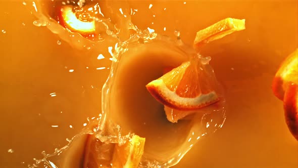 Pieces of Fresh Orange Fall Into Orange Juice with Splashes, Stock Footage