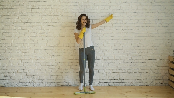 Beautiful Young Woman In Protective Gloves Is Singing Using A Mop And