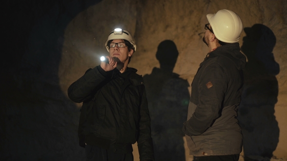 Two Speleologists with Flashlight Exploring the Cave with Fear in ...