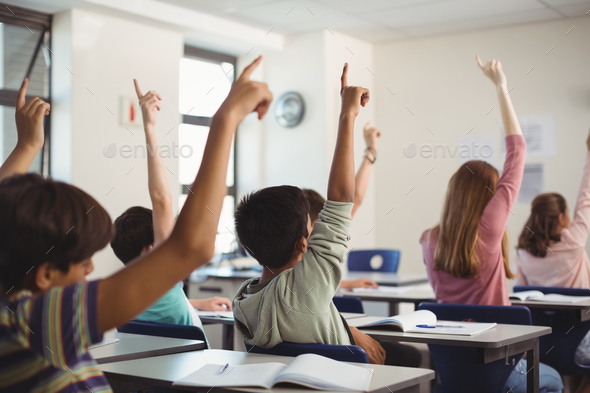 School kids raising hand in classroom Stock Photo by Wavebreakmedia