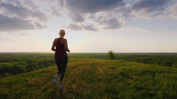 A Run in a Picturesque Place at Sunset. A Woman Runs Towards the Sun, a ...