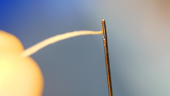 Threading the Eye of a Needle. Pulling the Thread Into the Needle Eye ...