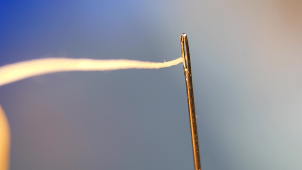 Threading the Eye of a Needle. Pulling the Thread Into the Needle Eye ...