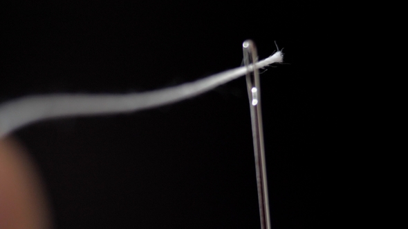 Threading the Eye of a Needle. Pulling the Thread Into the Needle Eye ...
