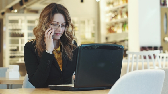 a Young Business Woman Works in a Cafe and Answers a Phone Call. Girl ...