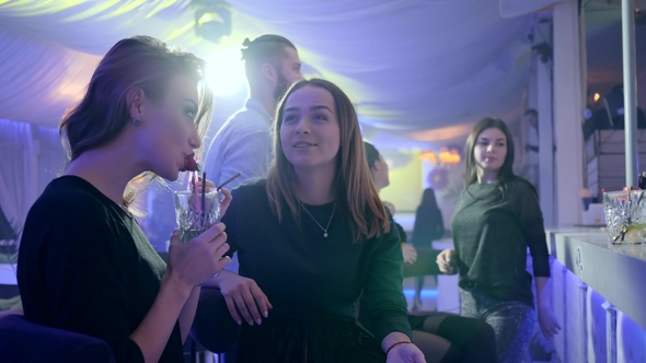 Young Woman Tells Secret to Her Friend at Club behind the Bar Counter ...