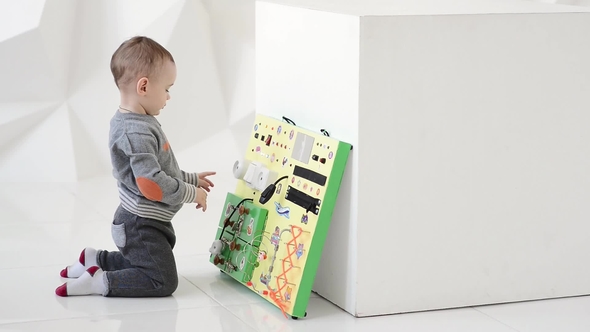 Little Baby Boy Intently Playing with Busy Board, Stock Footage | VideoHive