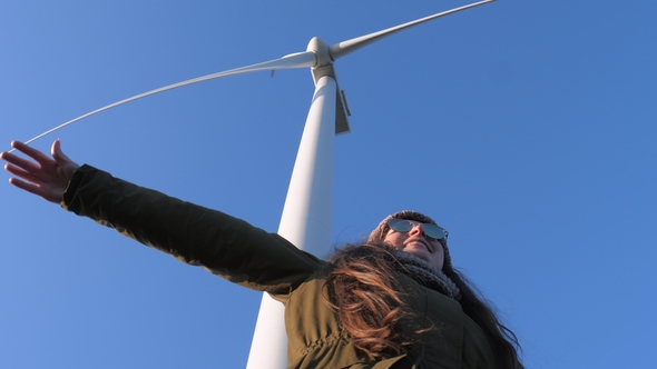 Cheerful Girl Having Fun and Waving Hands Under Wind Generator Against ...