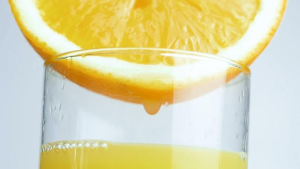 Footage of Droplet Slowly Dripping From Side of Orange in Glass of ...