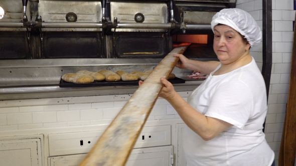 Traditional Italian Bakery. A Female Baker Takes Hot Bread Out of the ...