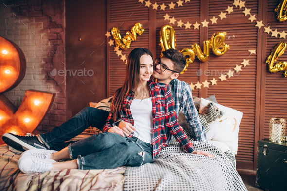 Couple hugs on the bed in bedroom with decoration Stock Photo by NomadSoul1