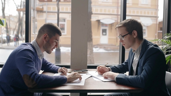 Two Men Are Working on Blueprint, Sitting at Table in Coffee Shop ...