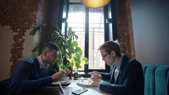 Two Young Friends Are Eating Food, Talking, Sitting at Table in ...