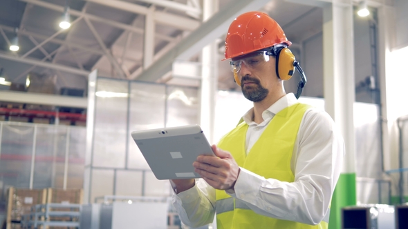 Factory Worker Is Standing and Working with His Tablet at a Factory ...