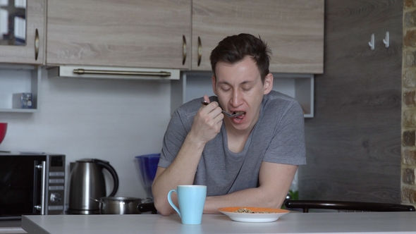 Young Handsome Man Eating Oatmeal Porridge in the Kitchen, Stock Footage