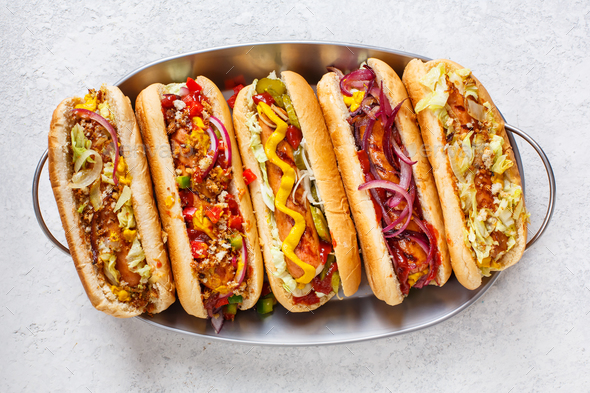 Hot dogs fully loaded with assorted toppings on a tray. Stock Photo by Vell