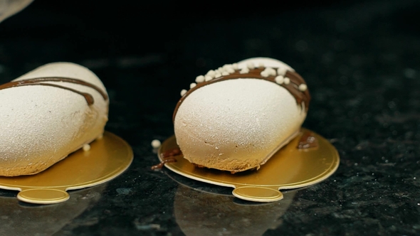 White Pastries on Golden Plates Being Decorated with Chocolate and Nuts ...