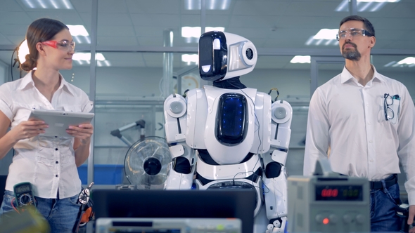 Robotic Humanoid Is Turning Its Head After a Male Engineer, Stock Footage