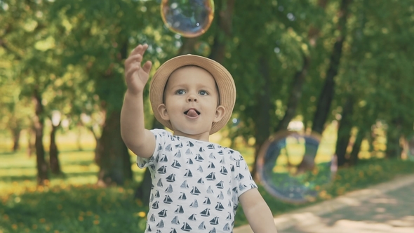 Little Boy in Hat Catching Bubbles. Little Child Playing with Parents ...