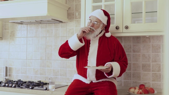 Santa Sits on Kitchen Furniture and Eats Cookies with Milk, Stock Footage