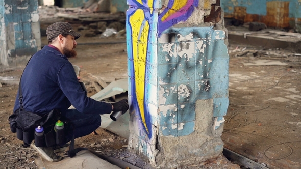 Modern Graffiti Painter Is Squatting Near Column in Old Abandoned ...