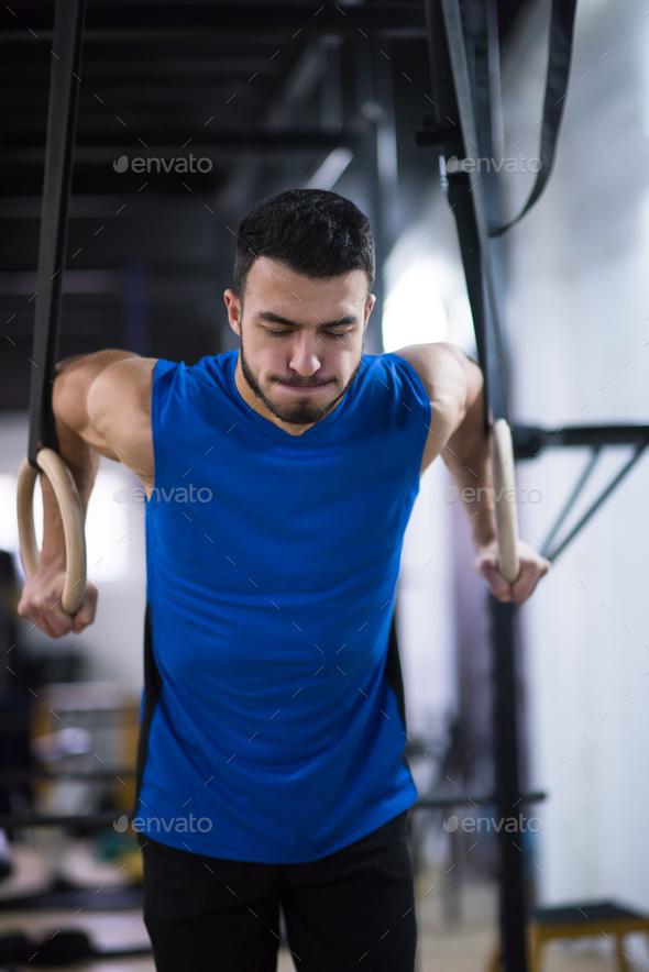 man working out pull ups with gymnastic rings Stock Photo by dotshock